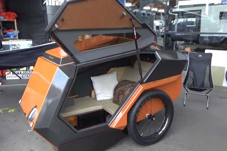 The Expedition camper trailer for bicycles has a seat and sleeping area